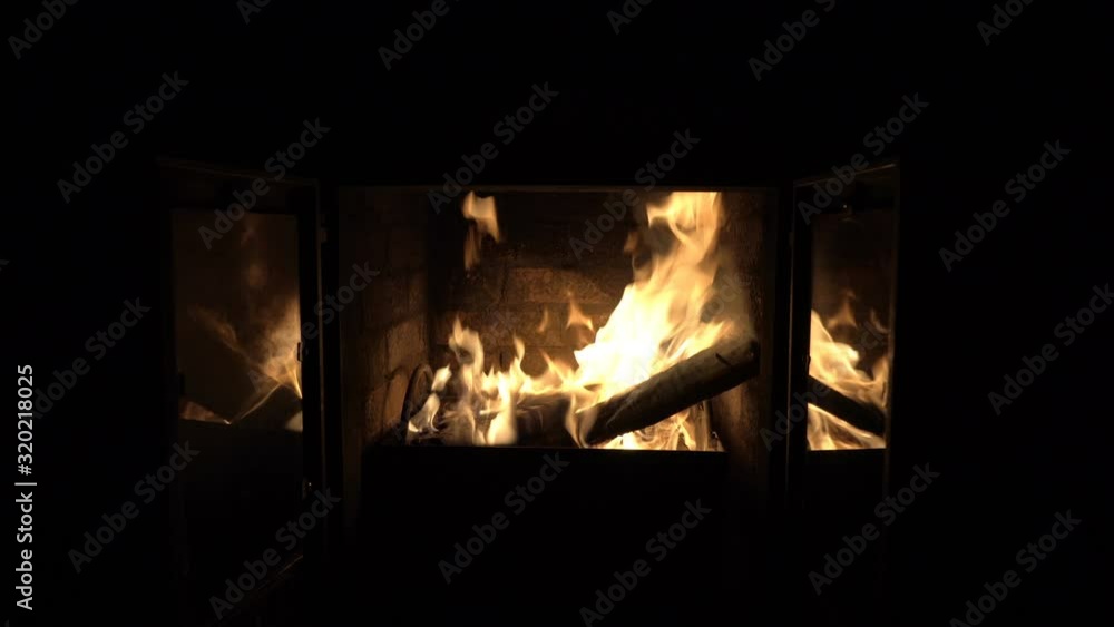 The glass door of the fireplace opens and a bright fire is visible ...