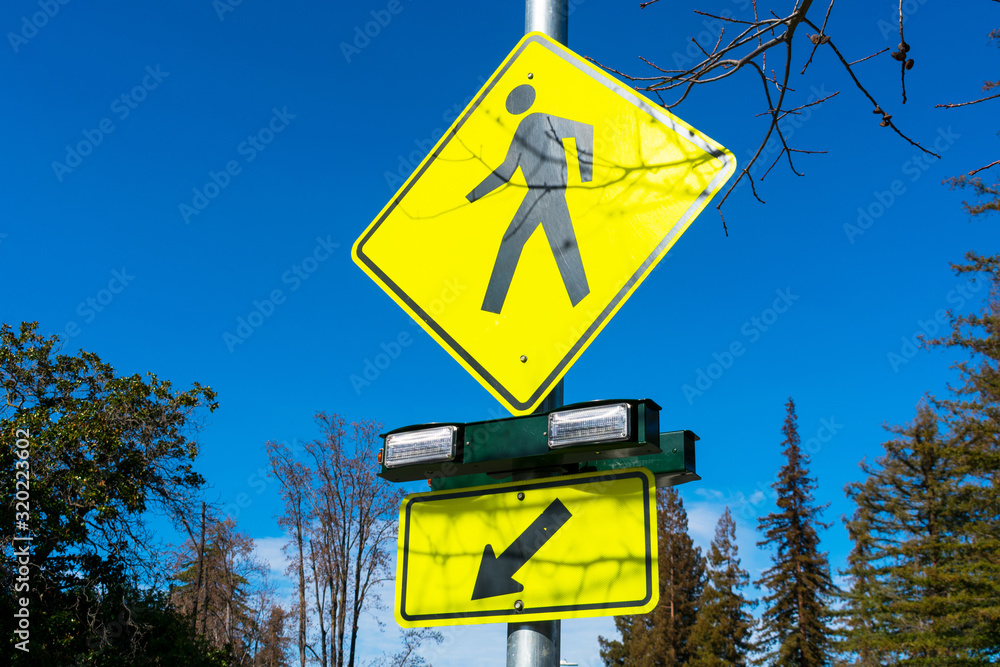 Pedestrian crossing sign with flashing lights during day time ...