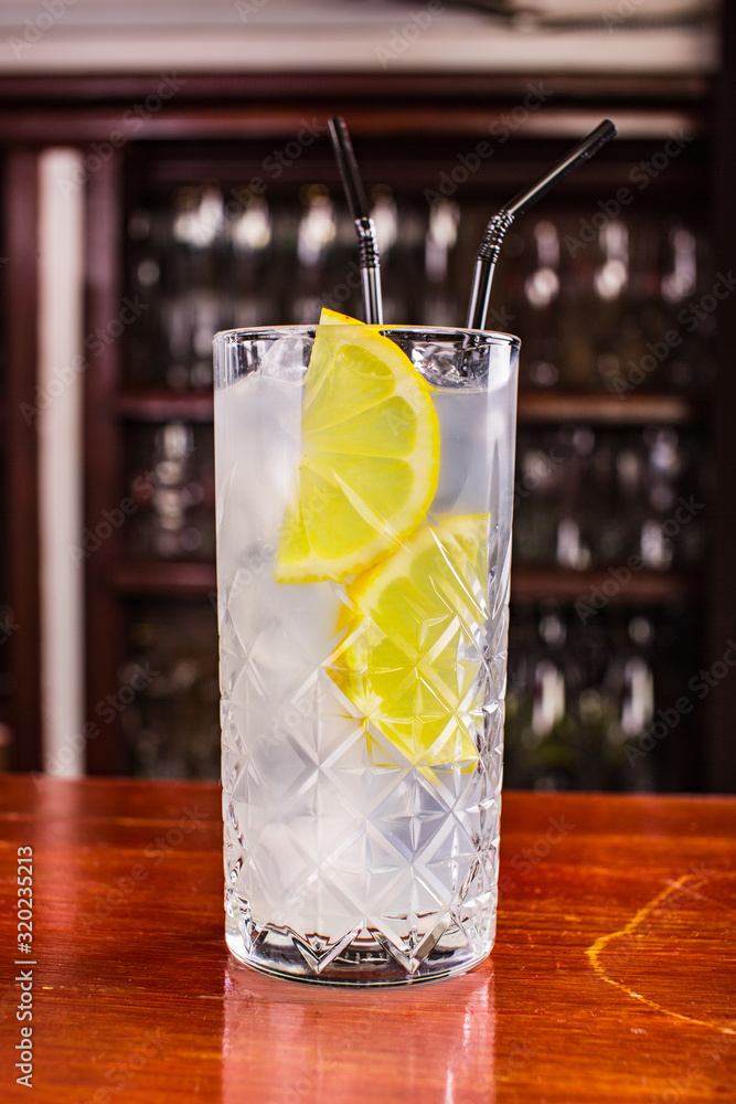 refresher cocktail with lemon, rozmarine on a wwoden stand a and bar ...