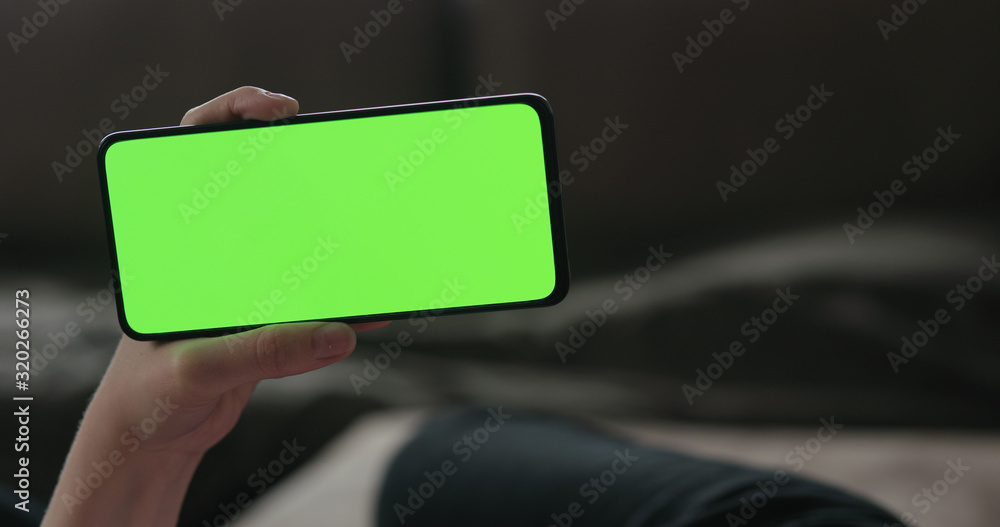 Young woman lying on a couch and using smartphone with horizontal green ...