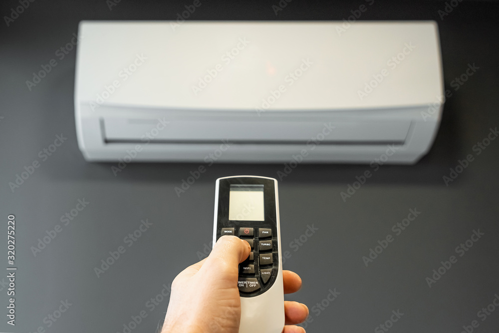 Hand with a remote control from an air conditioner close-up on a ...
