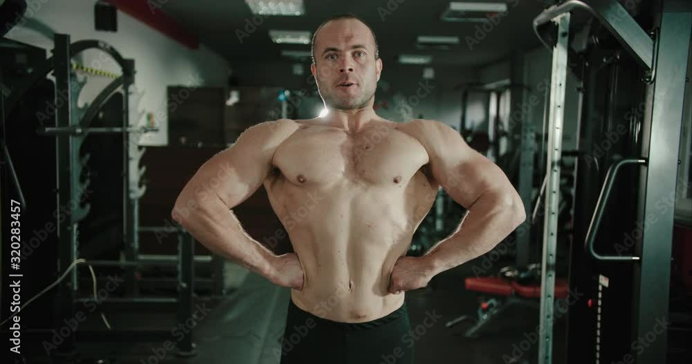 Muscular male bodybuilder athlete is tightening his chest muscles ...