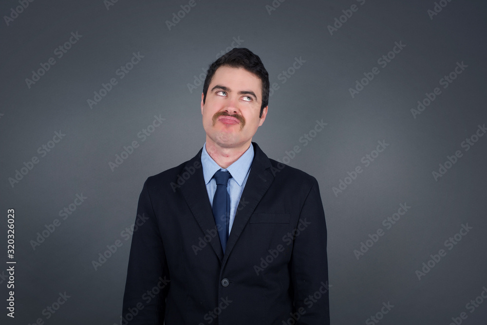 Gloomy, wondering young man face looking up lips together, being upset ...