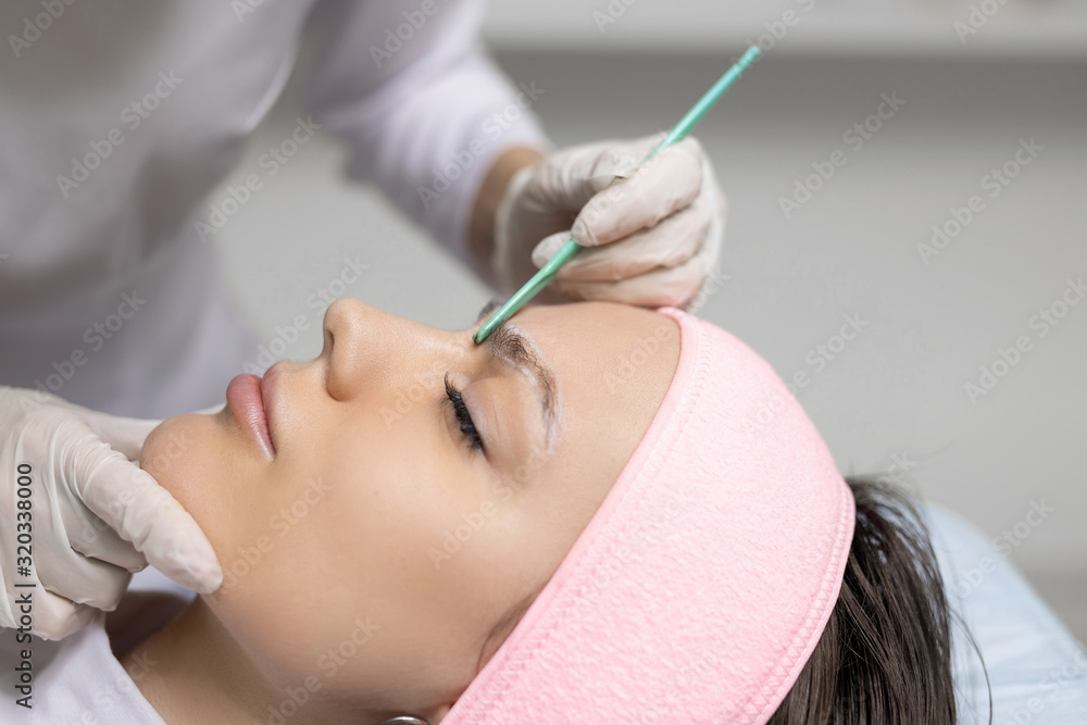 Permanent makeup, tattooing of eyebrows. Cosmetologist in white gloves ...