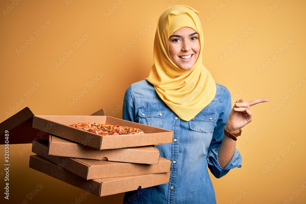 Young girl wearing muslim hijab holding boxes with Italian pizza over ...