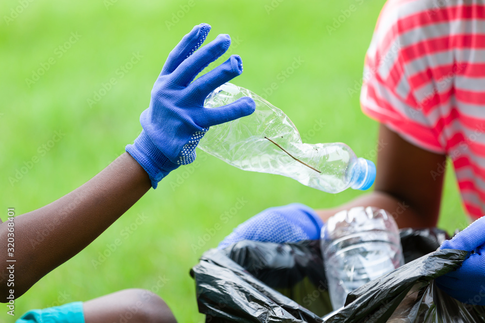 Group of kids school throwing garbage into a black bag in the park ...
