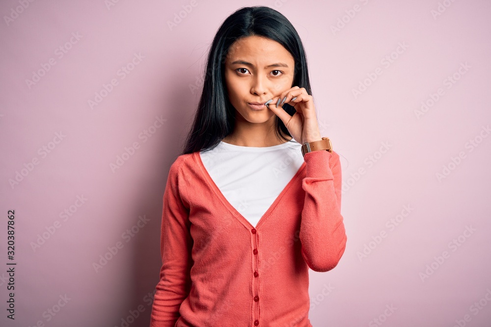 Young beautiful chinese woman wearing casual sweater over isolated pink ...