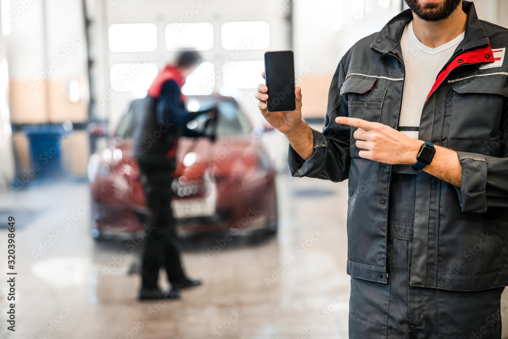 Caucasian mechanic pointing at his cellular phone Stock Photo | Adobe Stock