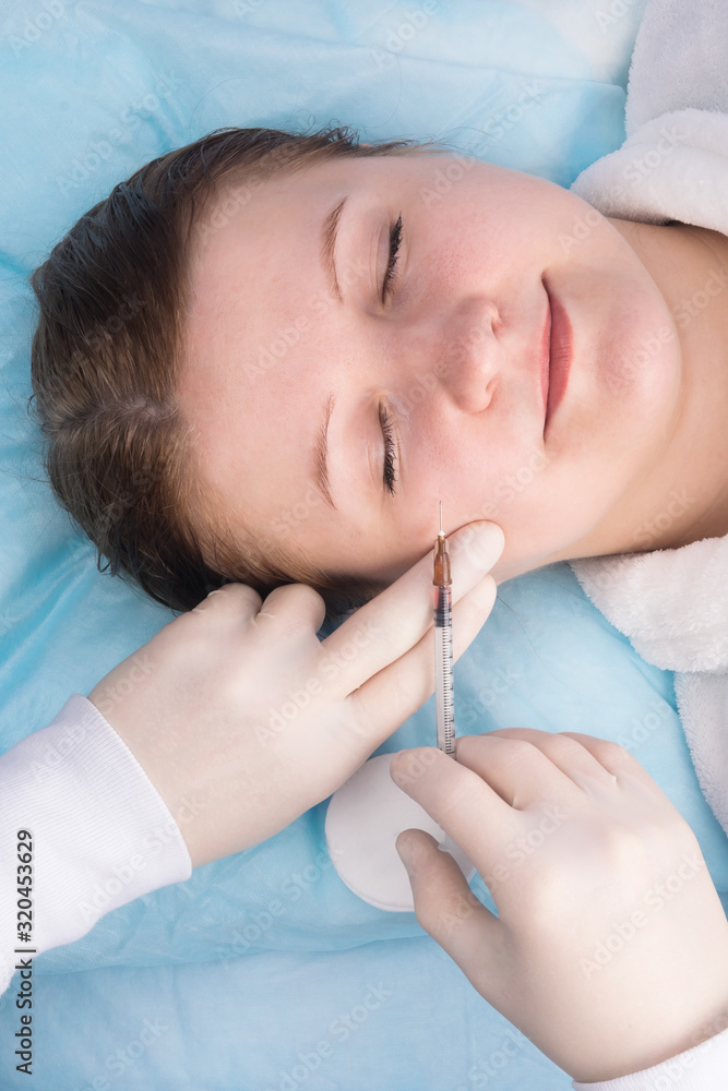 a woman is given an injection in the cheekbone to correct the shape of ...