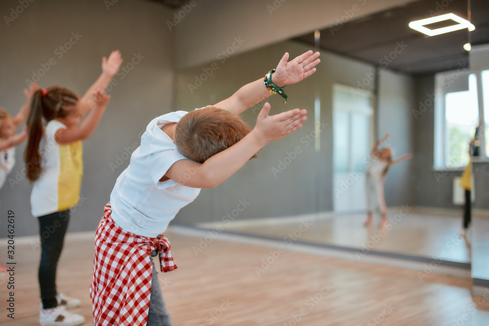 Warming up. Back view of boys and girls doing stretching exercises in ...