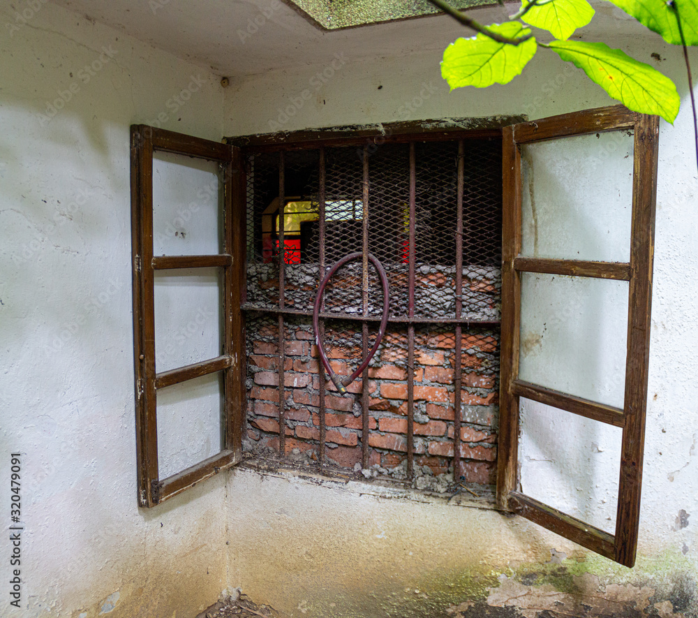 partially bricked up window in old chinese building with metal bars and ...