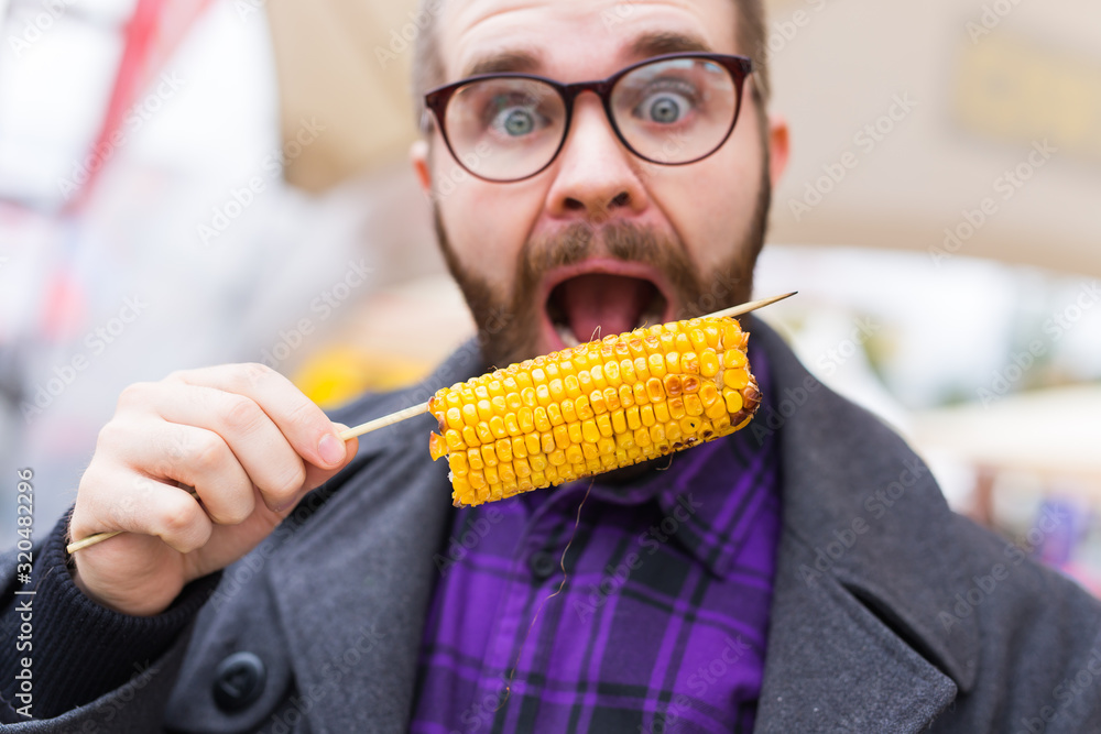 Vegetarian and meal concept - Handsome man eating street food corn at ...