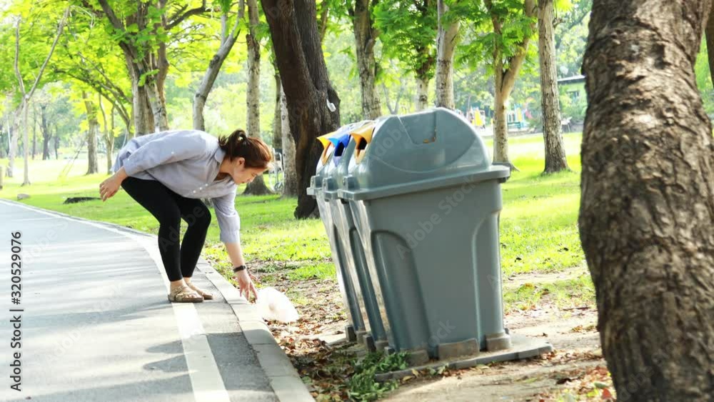 Video Stock Asian woman picking up litter from the floor into the trash ...