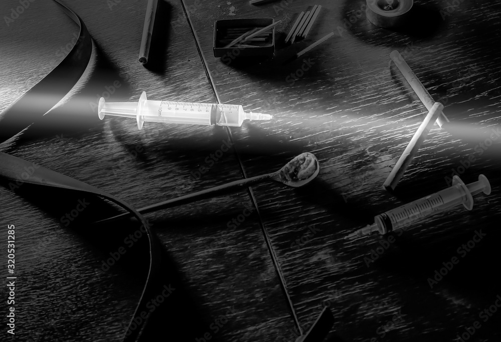 Needle syringe lying on the table. Drugs addict. Candle burning with ...