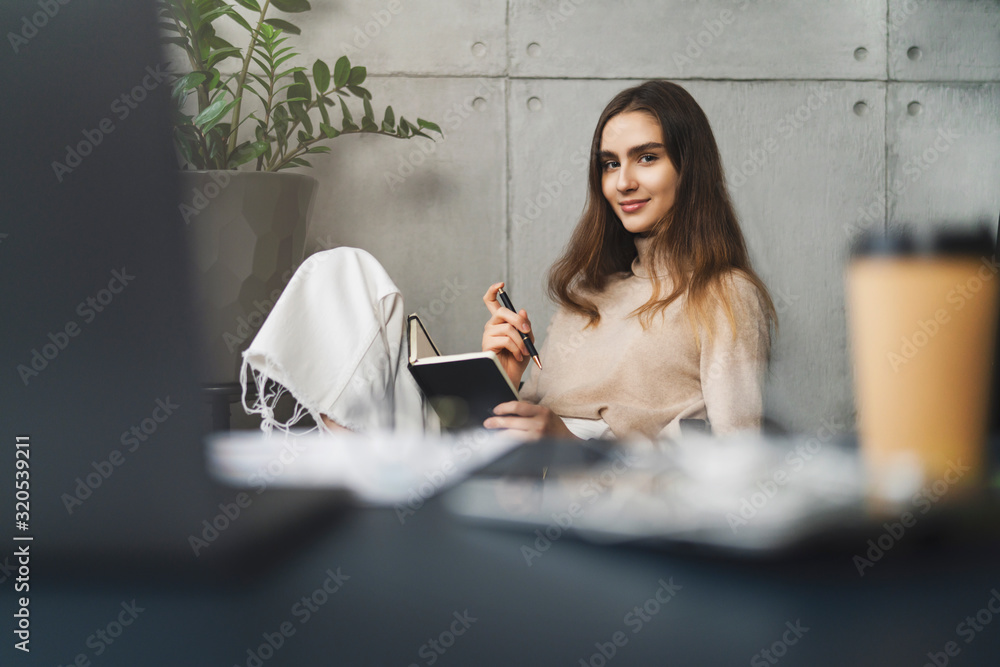 Female manager sitting at office desk, making notes in copybook. Young ...