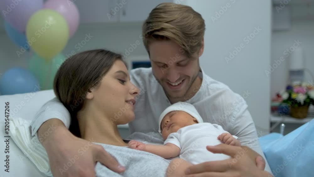 Happy family. Newborn baby resting in mother and father arms. Parents right after delivery in ...