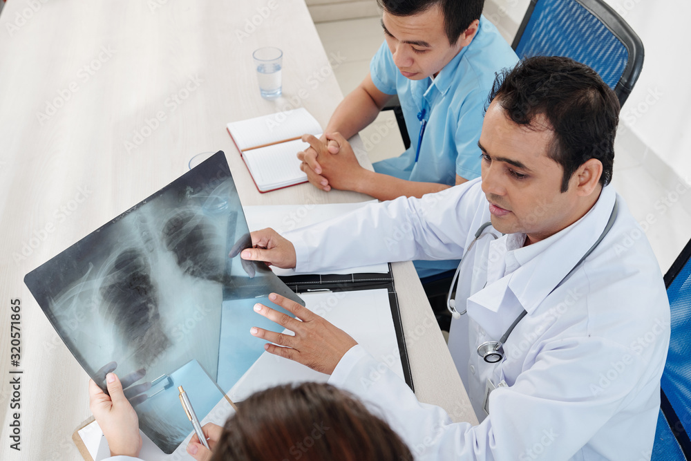 Pulmonologist discussing lungs x-ray of patient with his team and ...