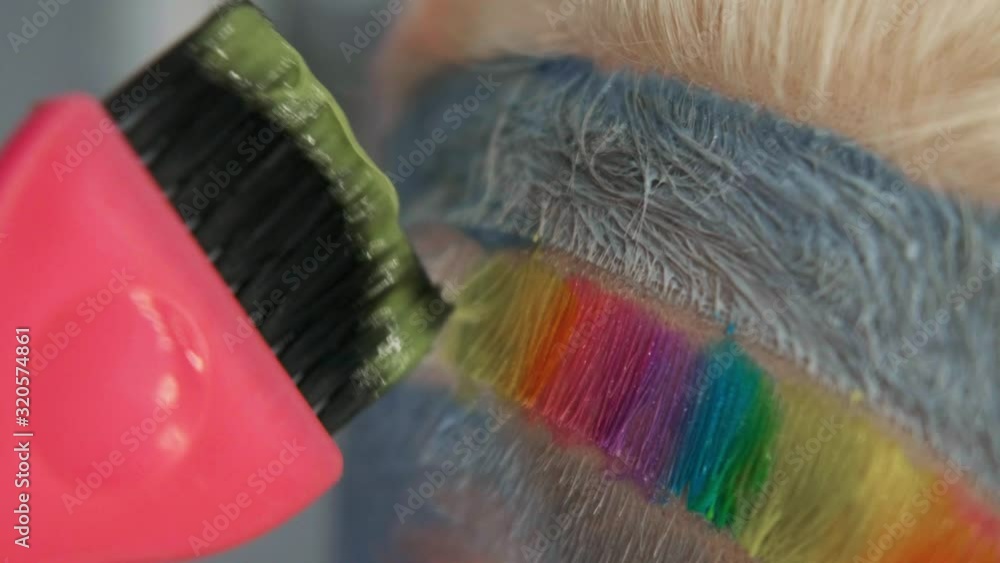 Hairdresser colorist puts paint on the hair with a brush. A short ...