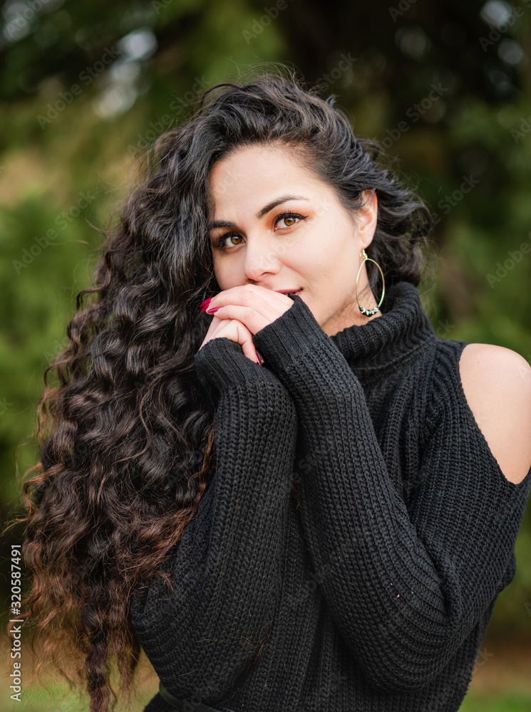 belle jeune brune aux cheveux longs et frisés en extérieur devant un ...