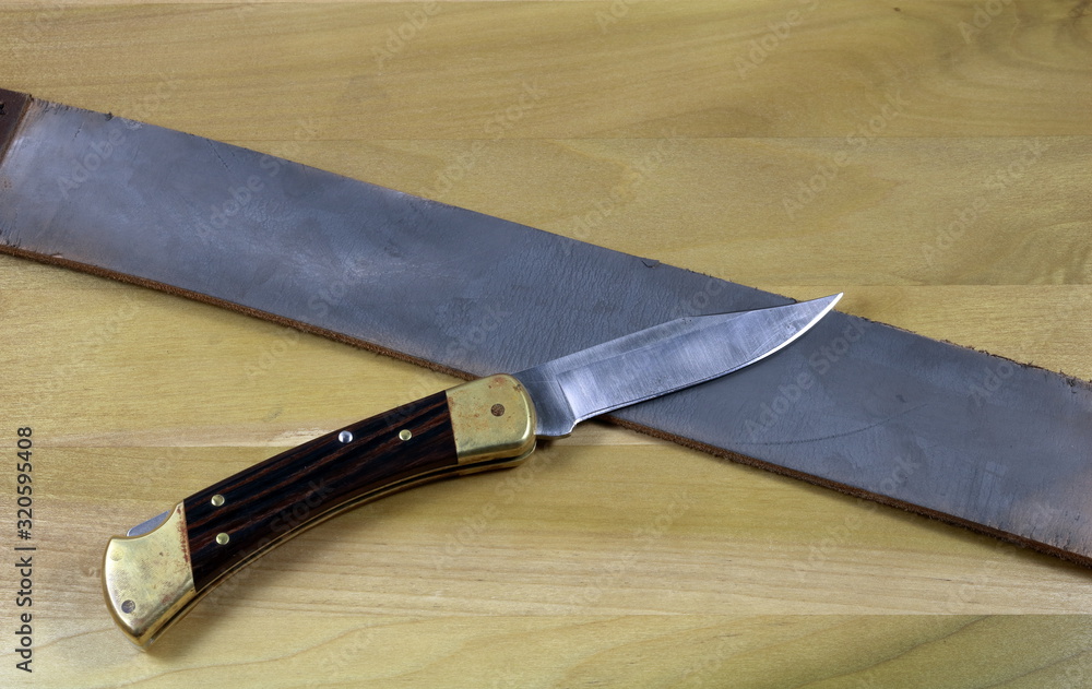 Used Hanging Razor Strop and hunting knife on wood textured board Stock ...