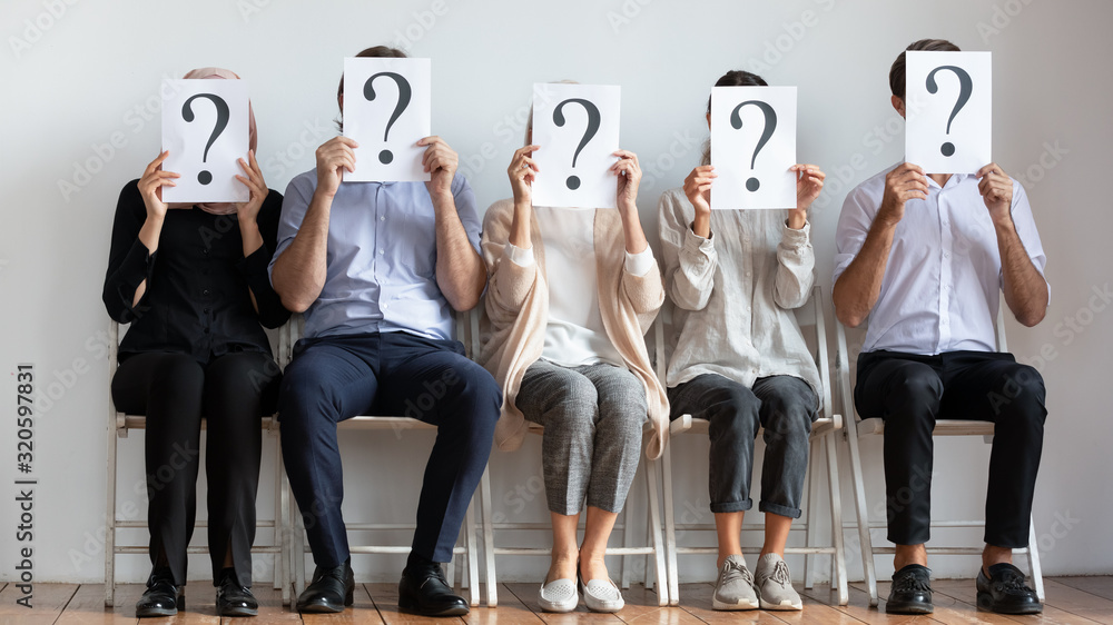 Diverse employees hold sheets with question marks wait for interview ...