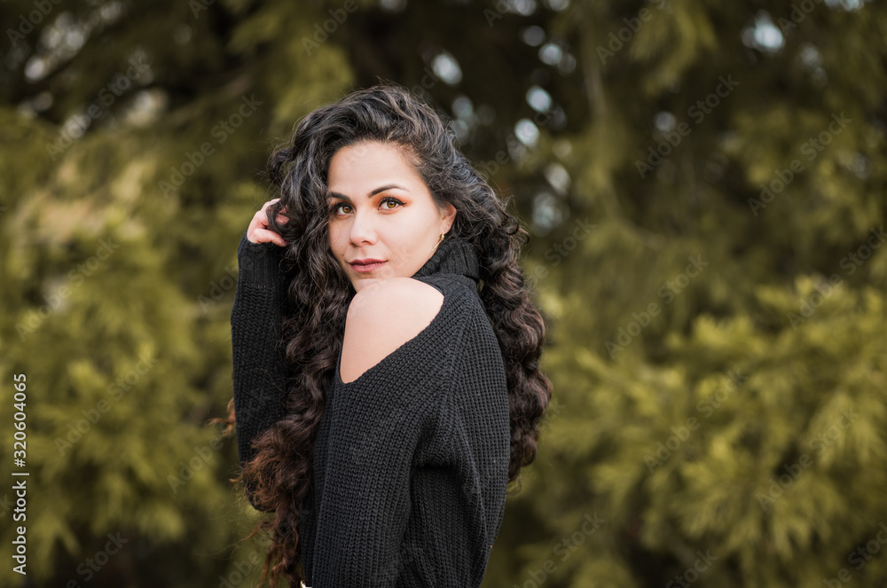 belle jeune brune aux cheveux longs et frisés en extérieur devant un ...