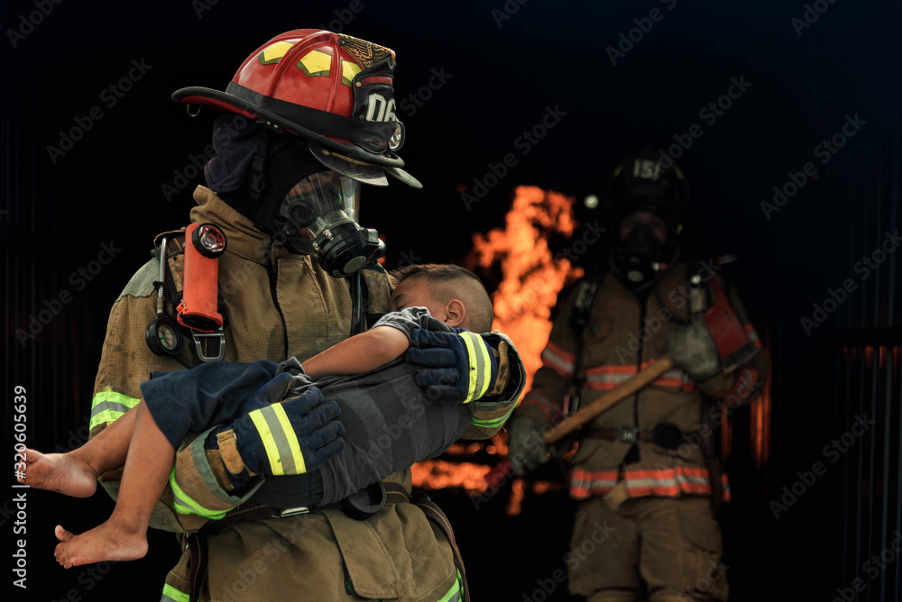 Rescue from fire. Firefighter team holding a boy on his hands and ...