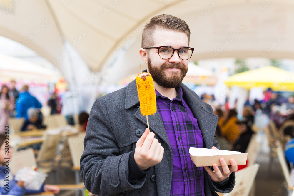 Vegetarian and meal concept - Handsome man eating street food corn at ...