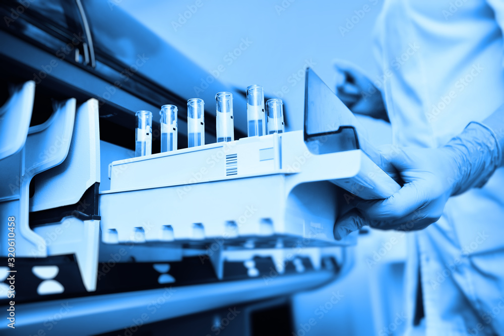 A scientist in a laboratory places test tubes with blood or urine in ...