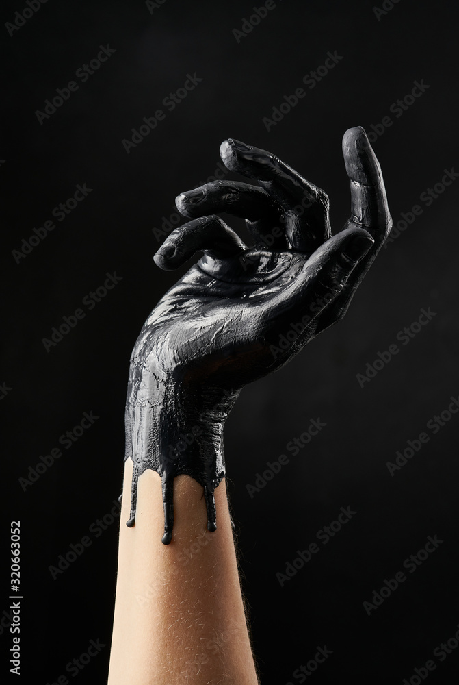 Female refined hand smeared with black acrylic paint on a black ...