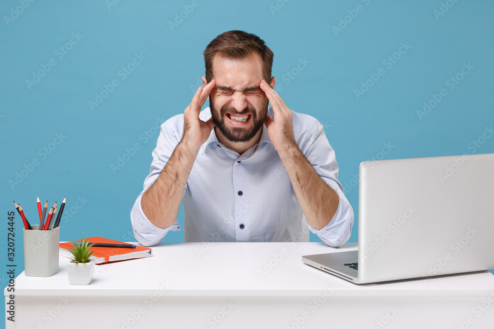 Exhausted sick young man in shirt sit work at desk with pc laptop ...