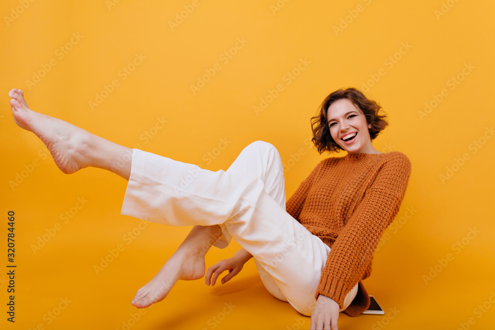 Smiling barefooted girl with eacstatic face expression posing with legs ...
