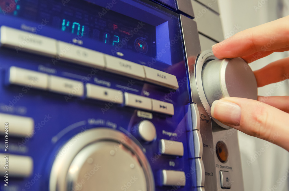 Fotka „Manual volume control in the music center. A woman's hand ...