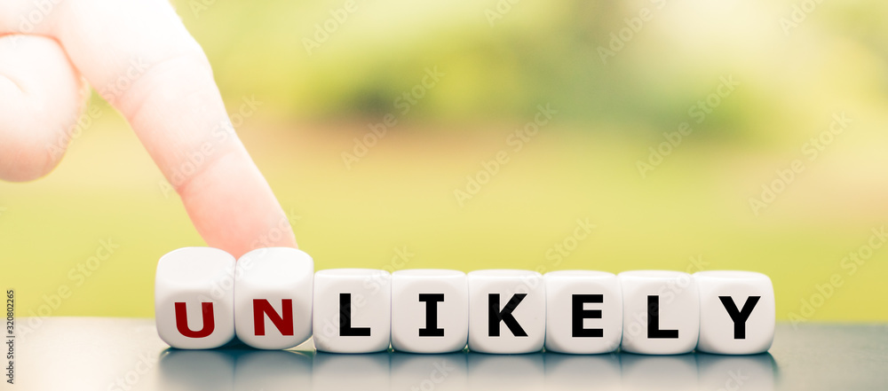 Hand turns dice and changes the word "unlikely" to "likely". Stock ...