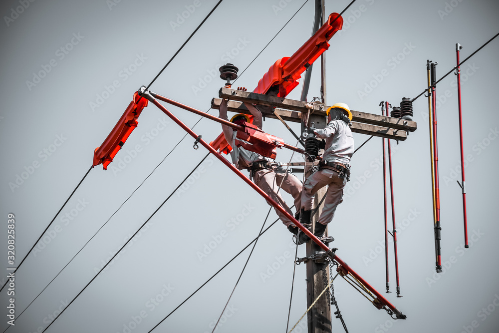 Two linemans use devices that are insulated for maintenance high ...