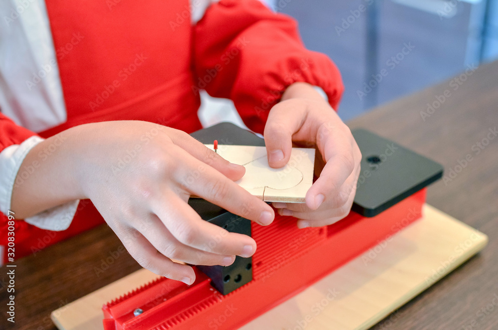 Boy is learning woodworking with a wood-crafting machine tool. Sanding ...
