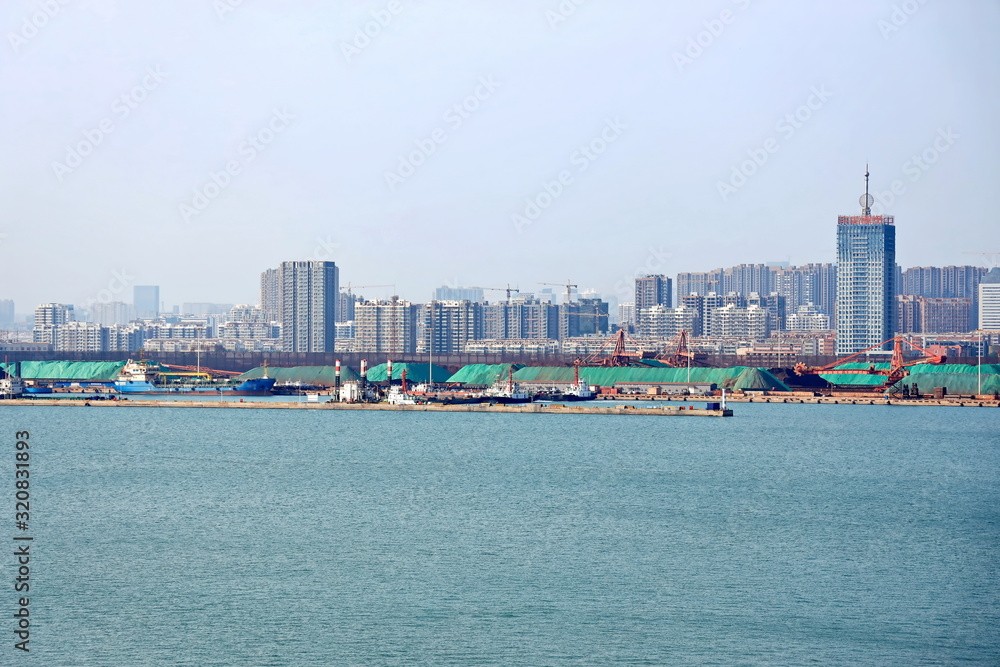 Panoramic views of piers, sea vessels, tugboats and the city of Rizhao ...