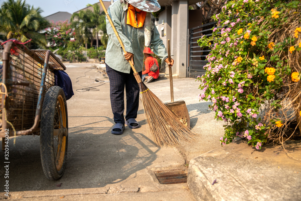 Workers are sweeping the pavement with broom that fall on the street ...