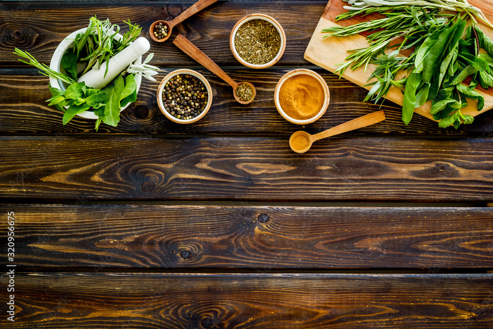 Making spices. Herbs in motar and dry flavorings on dark wooden desk ...