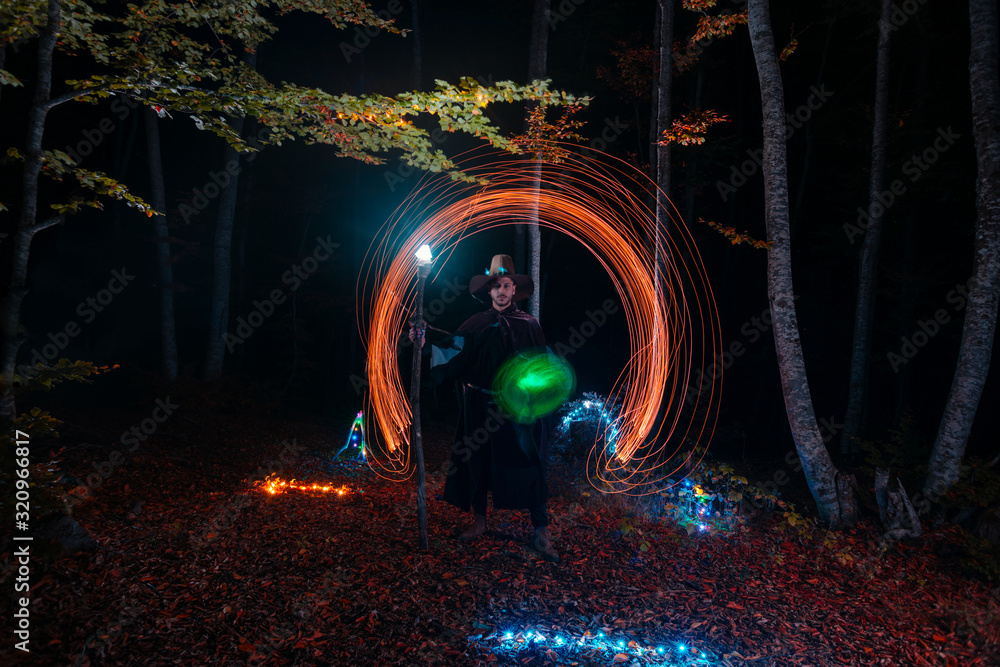 Sorcerer (magician) casting a spell while standing in the magical woods ...