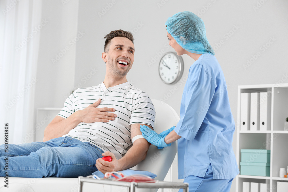 Female doctor preparing male donor for blood transfusion in hospital ...
