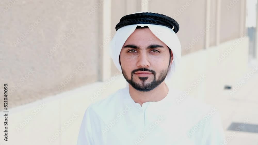 Arab man looks up to the camera smiling. Happy Arabic Emirati national ...