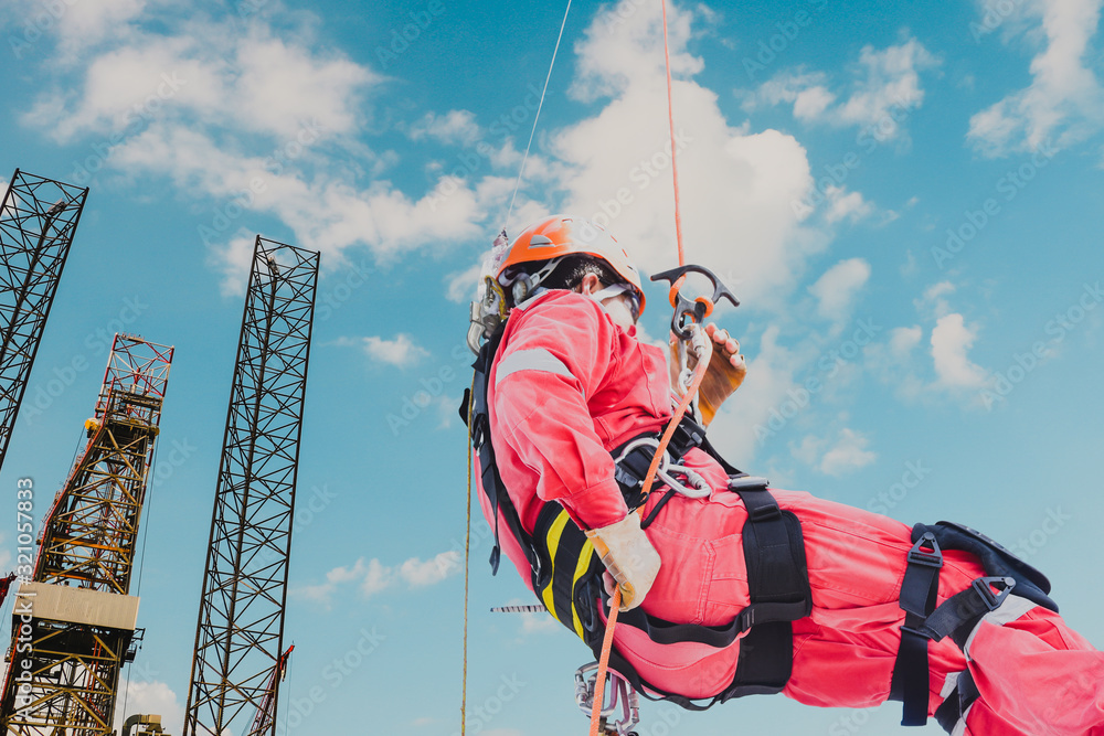 Rope access worker, wearing full safety body harness, face shield ...