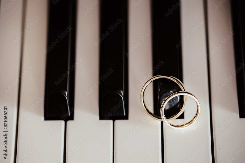Piano keyboard backdrop. Golden wedding rings. Symbol of love. Love ...