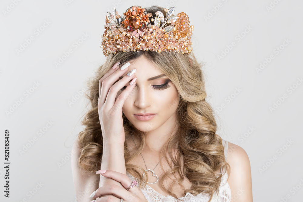Sad Beautiful blonde girl in a golden crown on white grey background ...