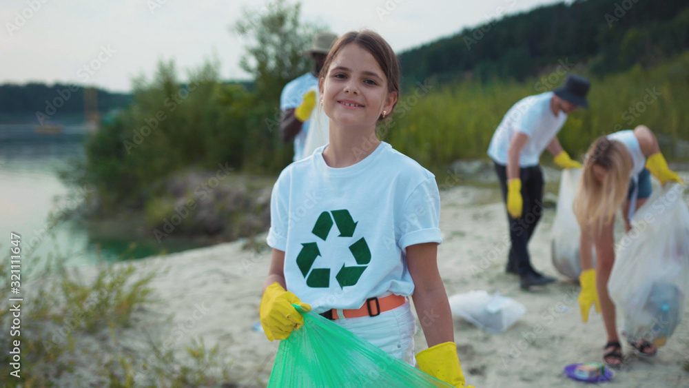 Adorable kid cleaning nature landscape from trash with environmental ...