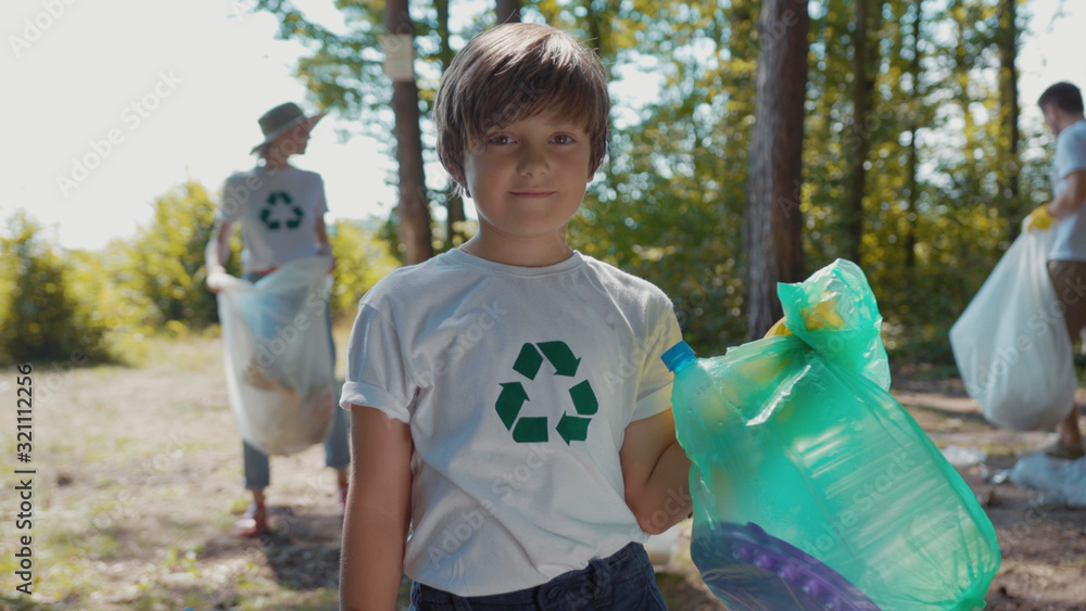 Happy boy voluteers activists child in gloves tidying up rubbish in ...
