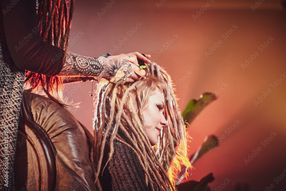 Process of dreadlocks making in the hair studio, blond girl receives a ...