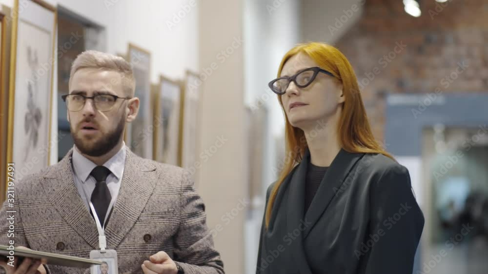 Professional male gallery docent holding clipboard and pointing at ...