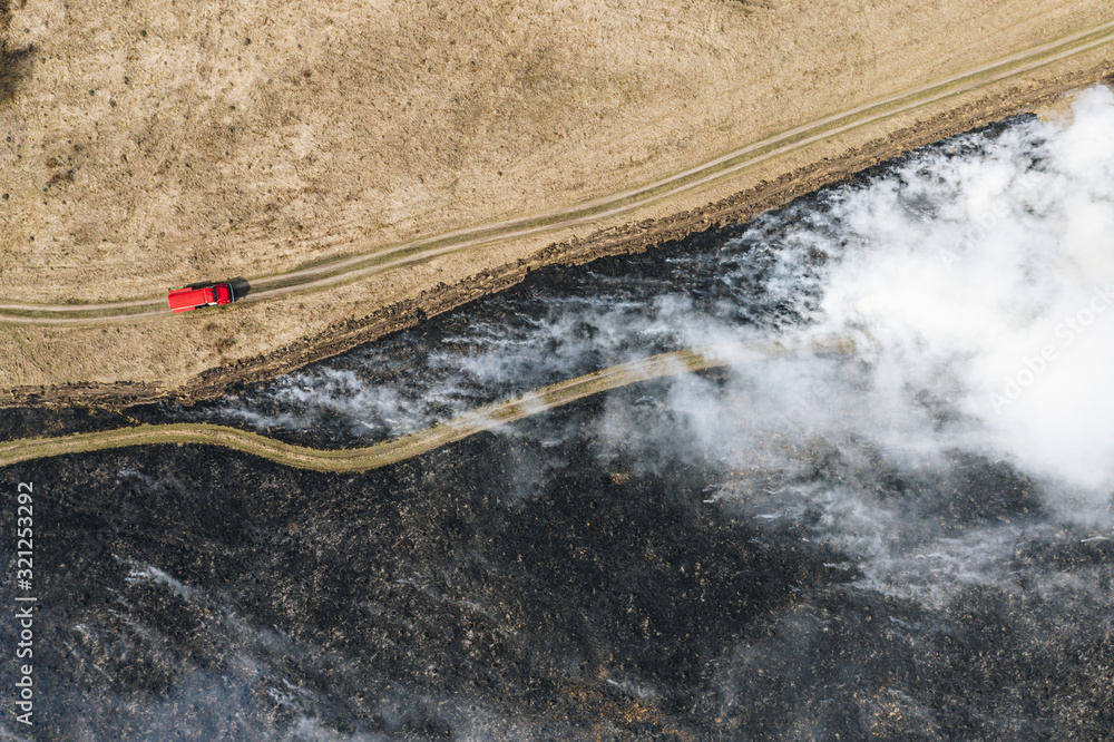 Field fire and red fire truck near firebreak, aerial top down view. Dry ...